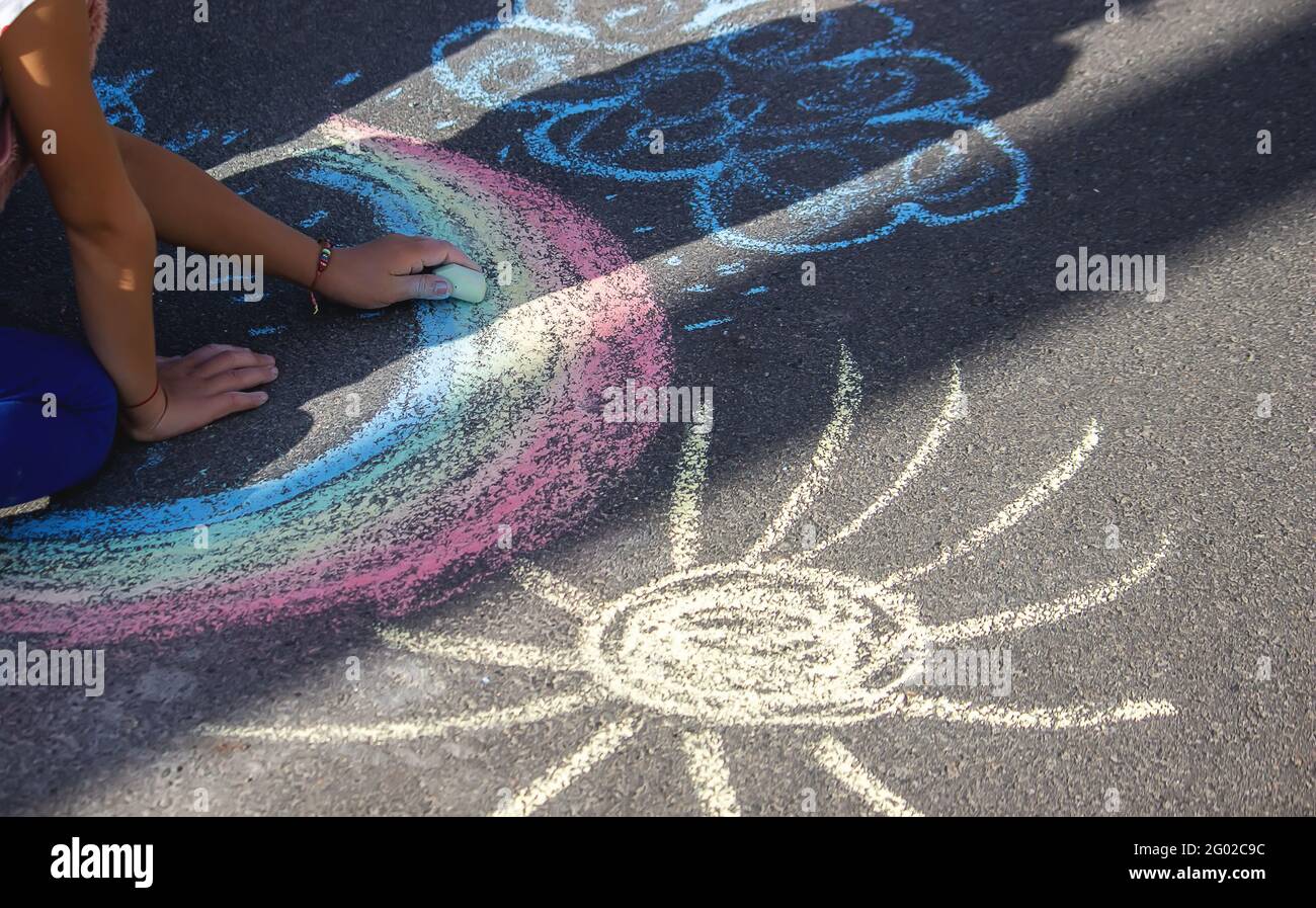 Cute little child draws the sun with chalk outdoors, summer time, chalk ...