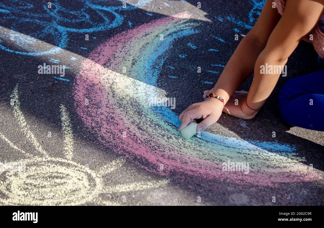Cute little child draws the sun with chalk outdoors, summer time, chalk ...