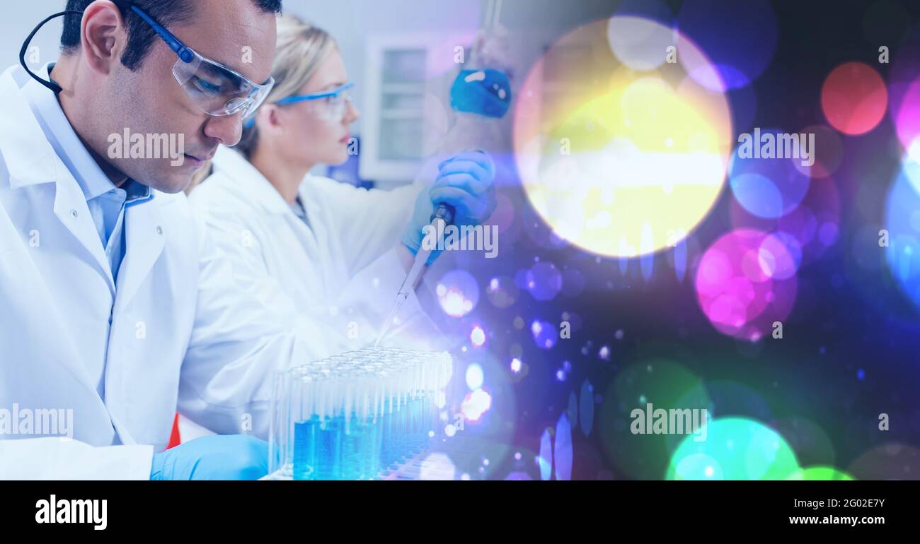 Composition of male and female lab technicians at work, with colourful bokeh copy space to right ...