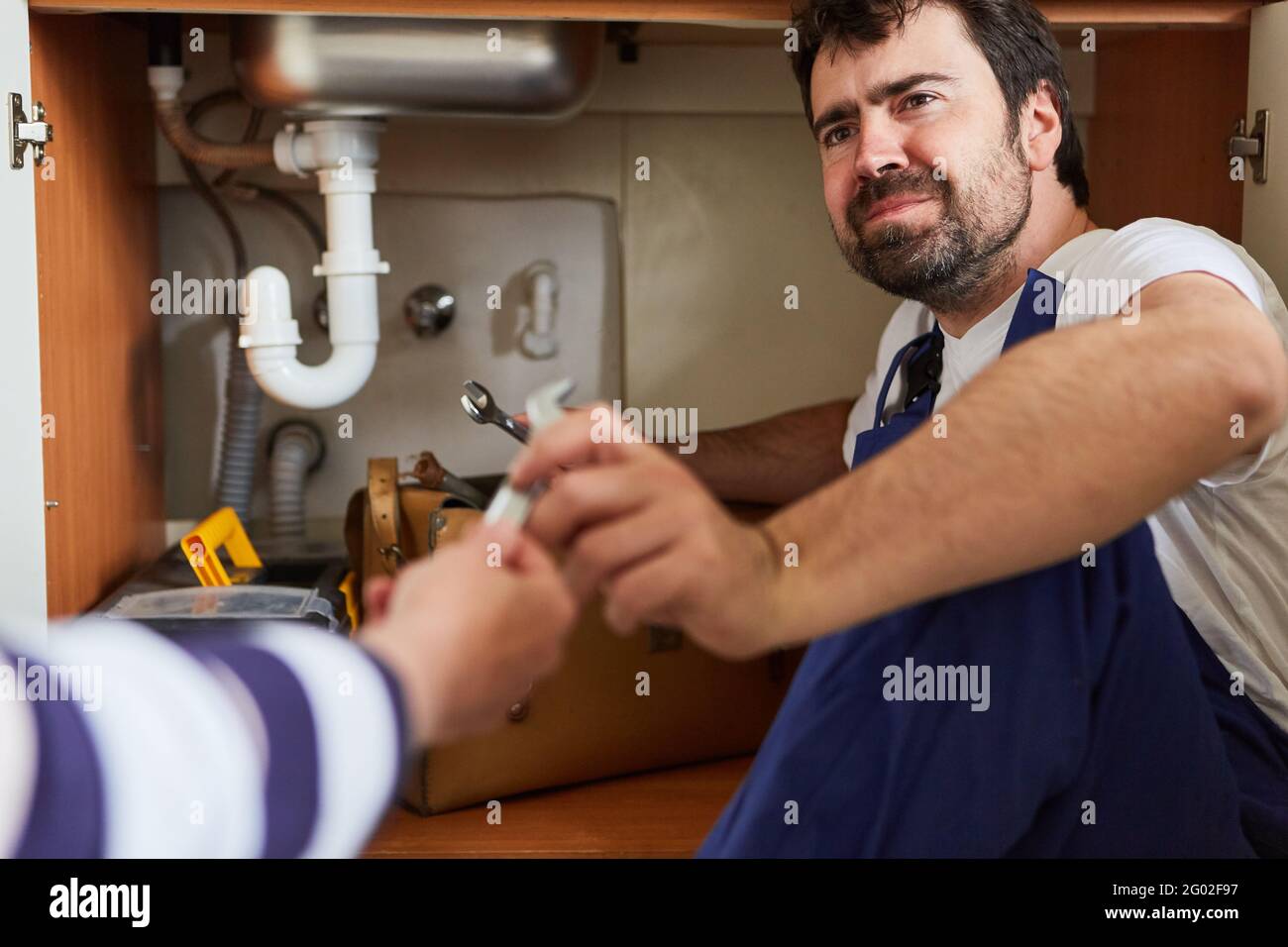 A stressed handyman needs help repairing the sink in the kitchen Stock ...