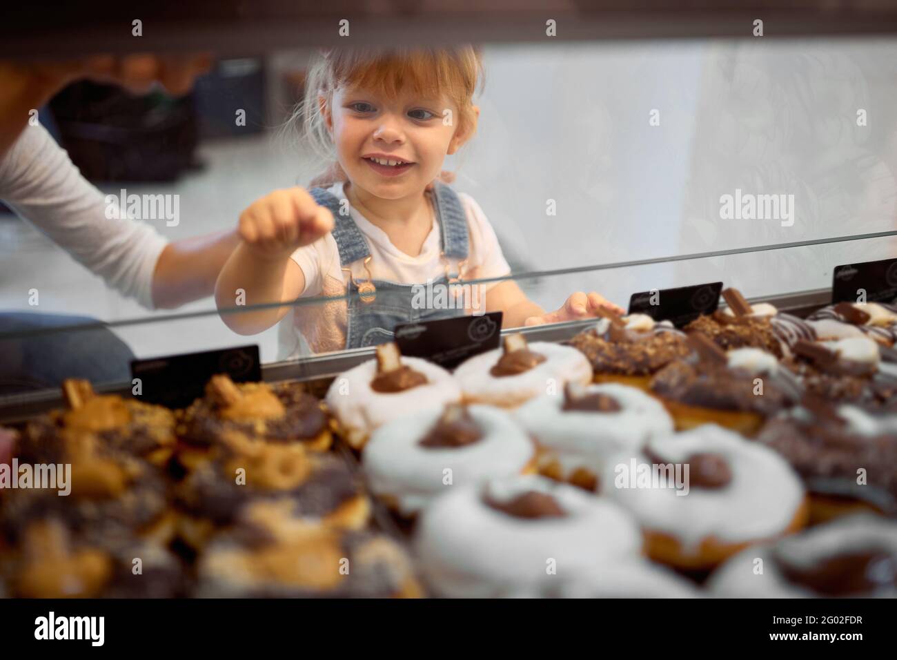 Portrait of a toddler girl picking up tasty donuts at store Stock Photo ...