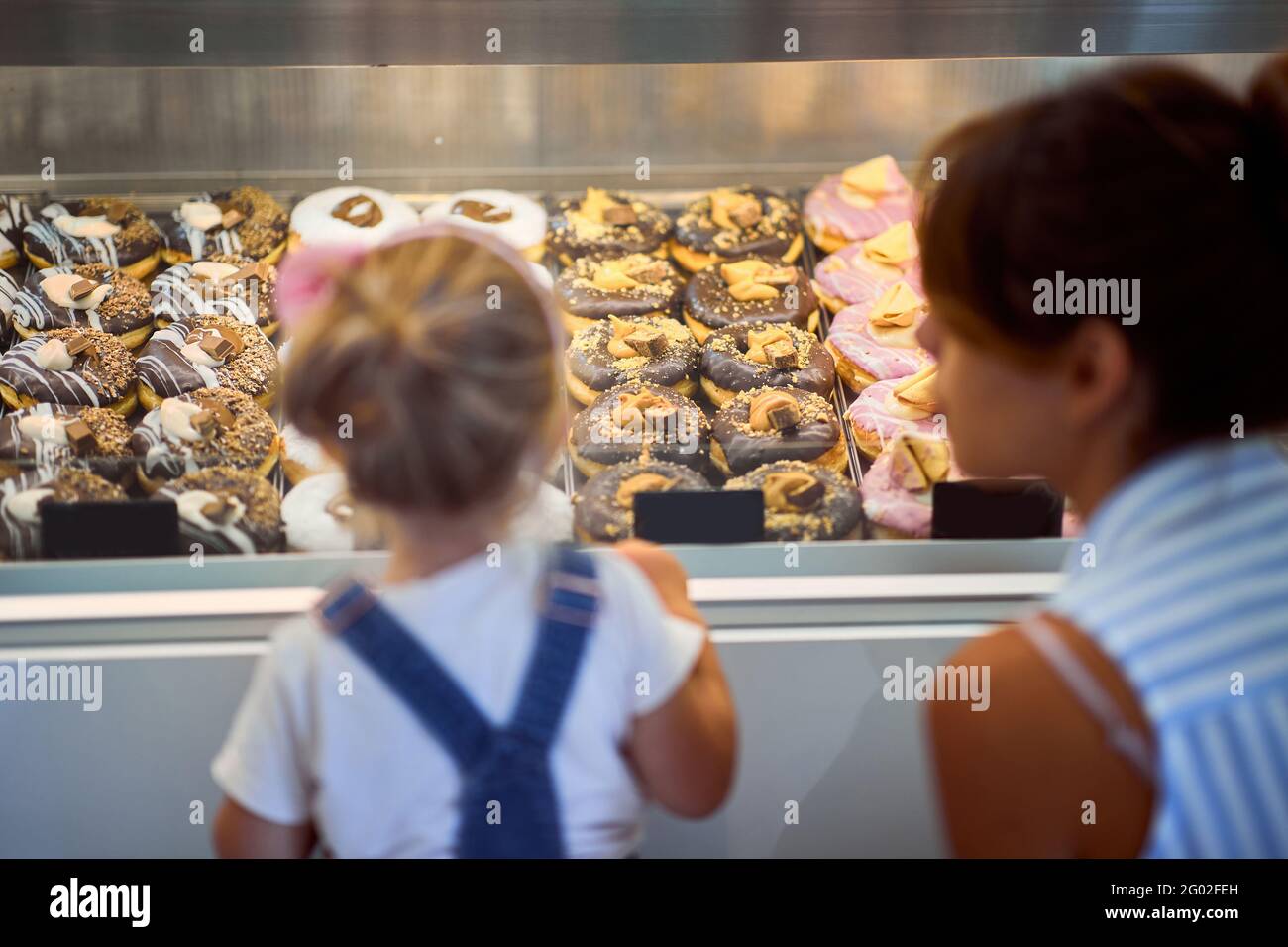 Mother and daughter buying glazed donuts together at store Stock Photo ...