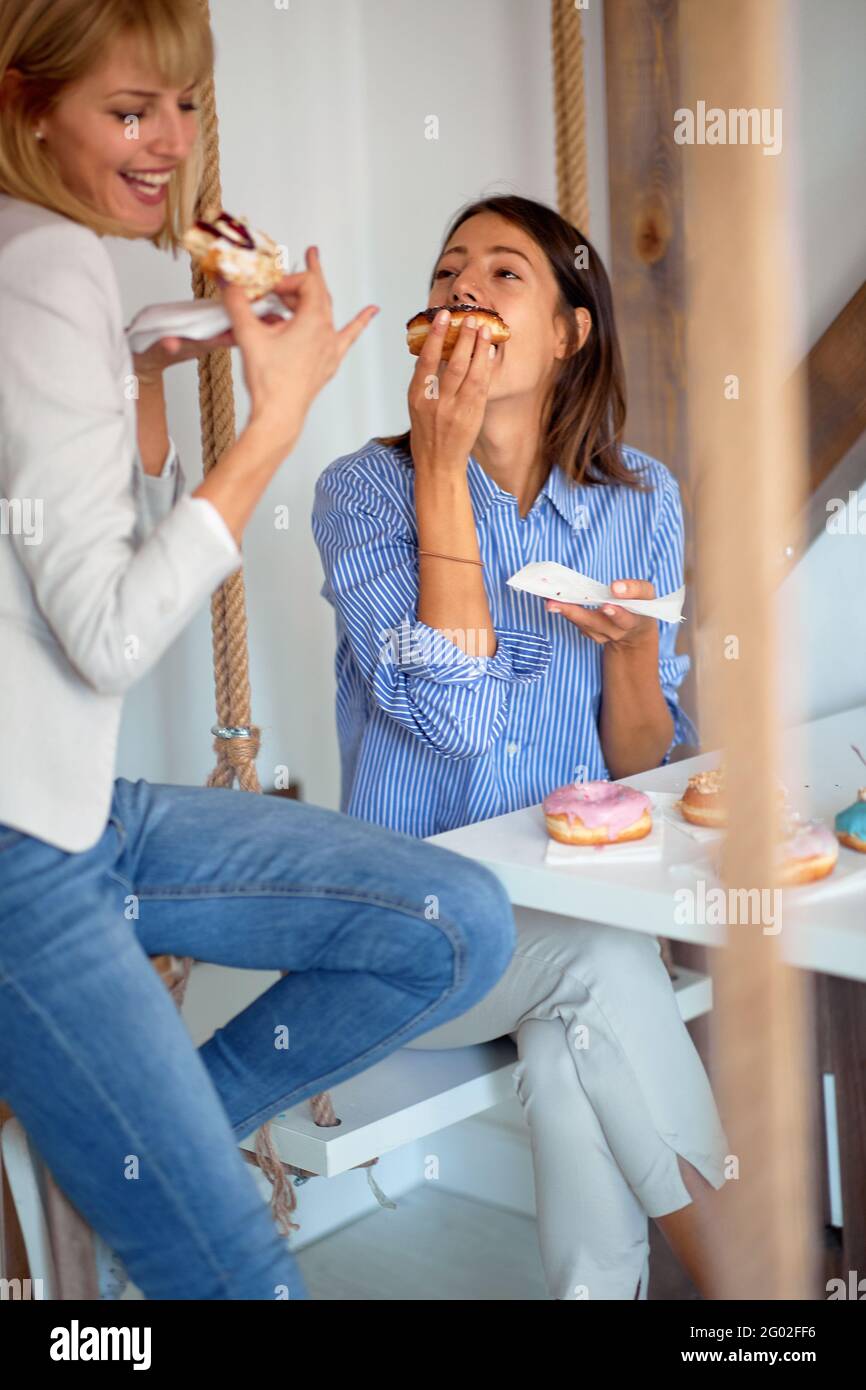 Two female friends in a pastry shop are in ecstasy while eating ...