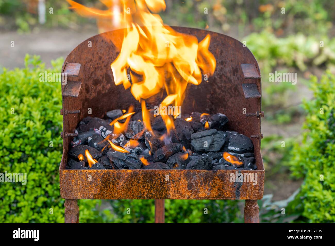 Barbecue grill with fire and charcoal, flame burning in the garden ...