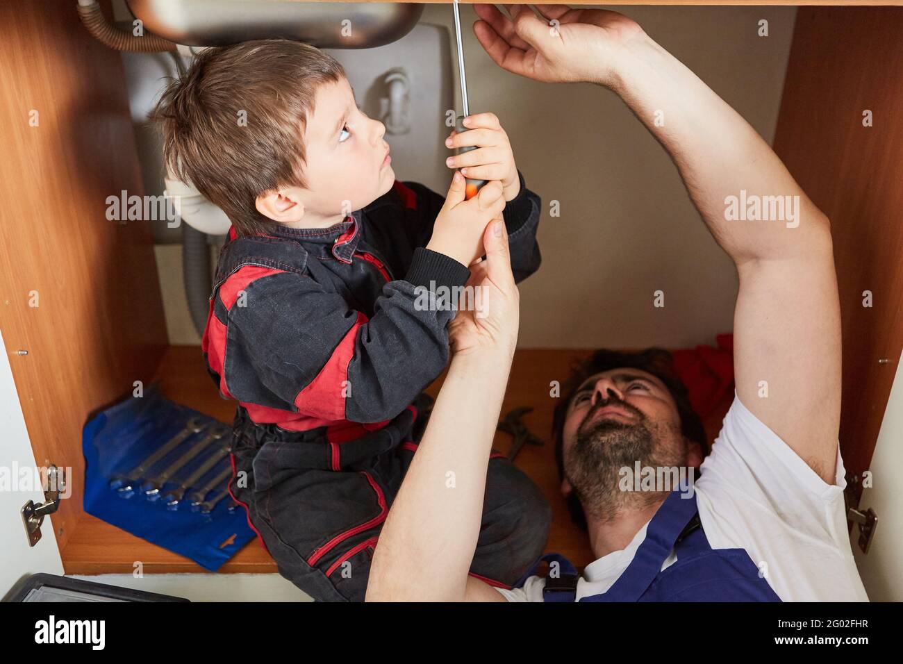 Boy helps his father as a do-it-yourselfer to repair a broken kitchen ...