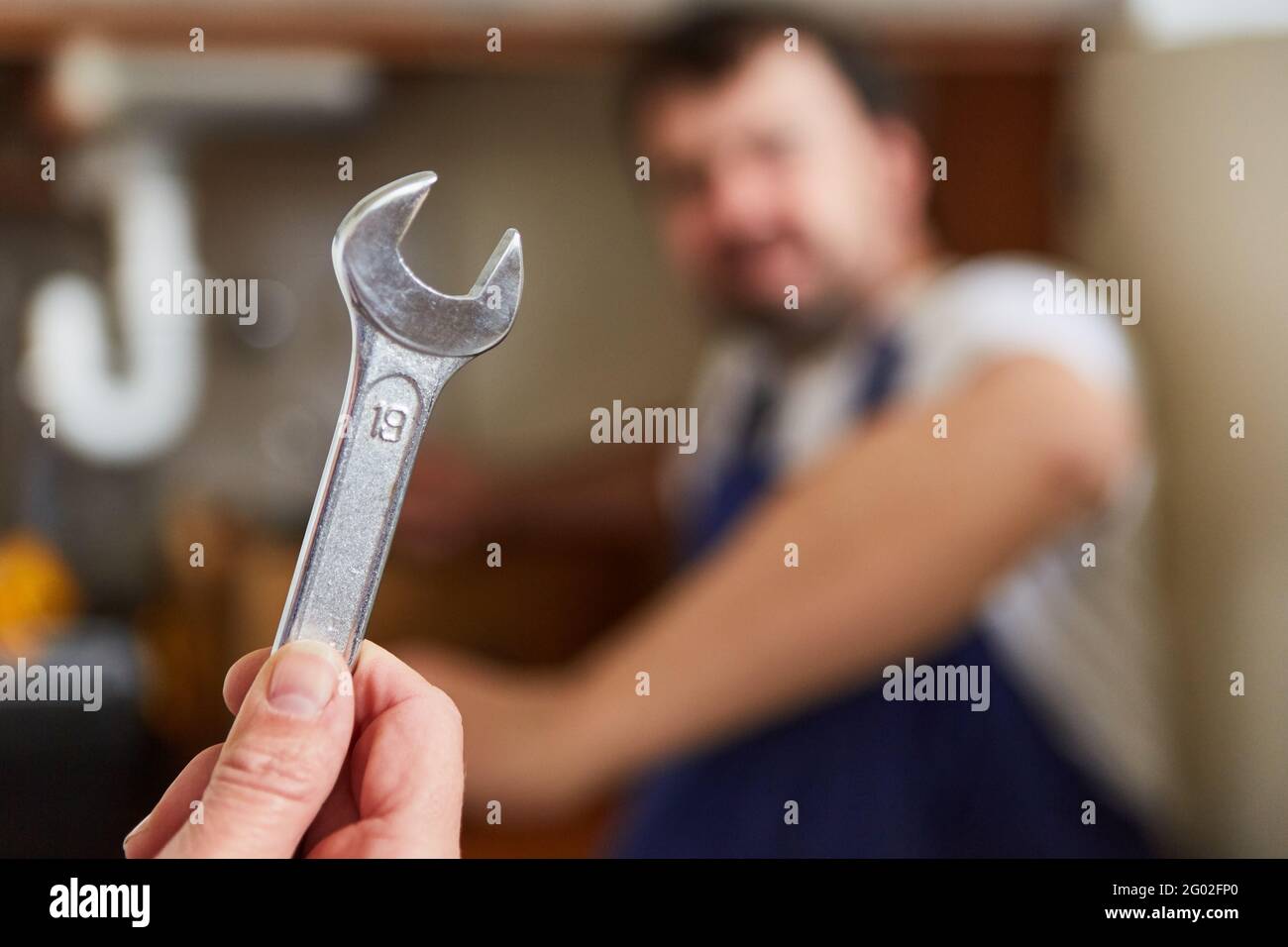Hand holds wrench as a plumber's hand tool for installation and ...