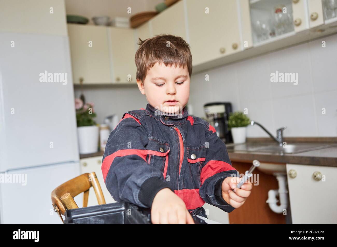Boy in kitchen sorts tools in toolbox while handyman playing Stock ...