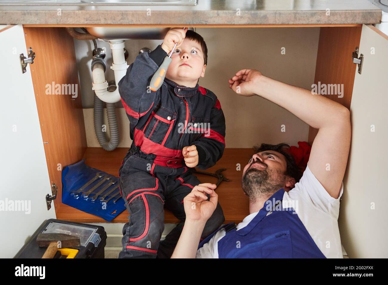 Son helps dad as a handyman install a sink in the kitchen Stock Photo ...