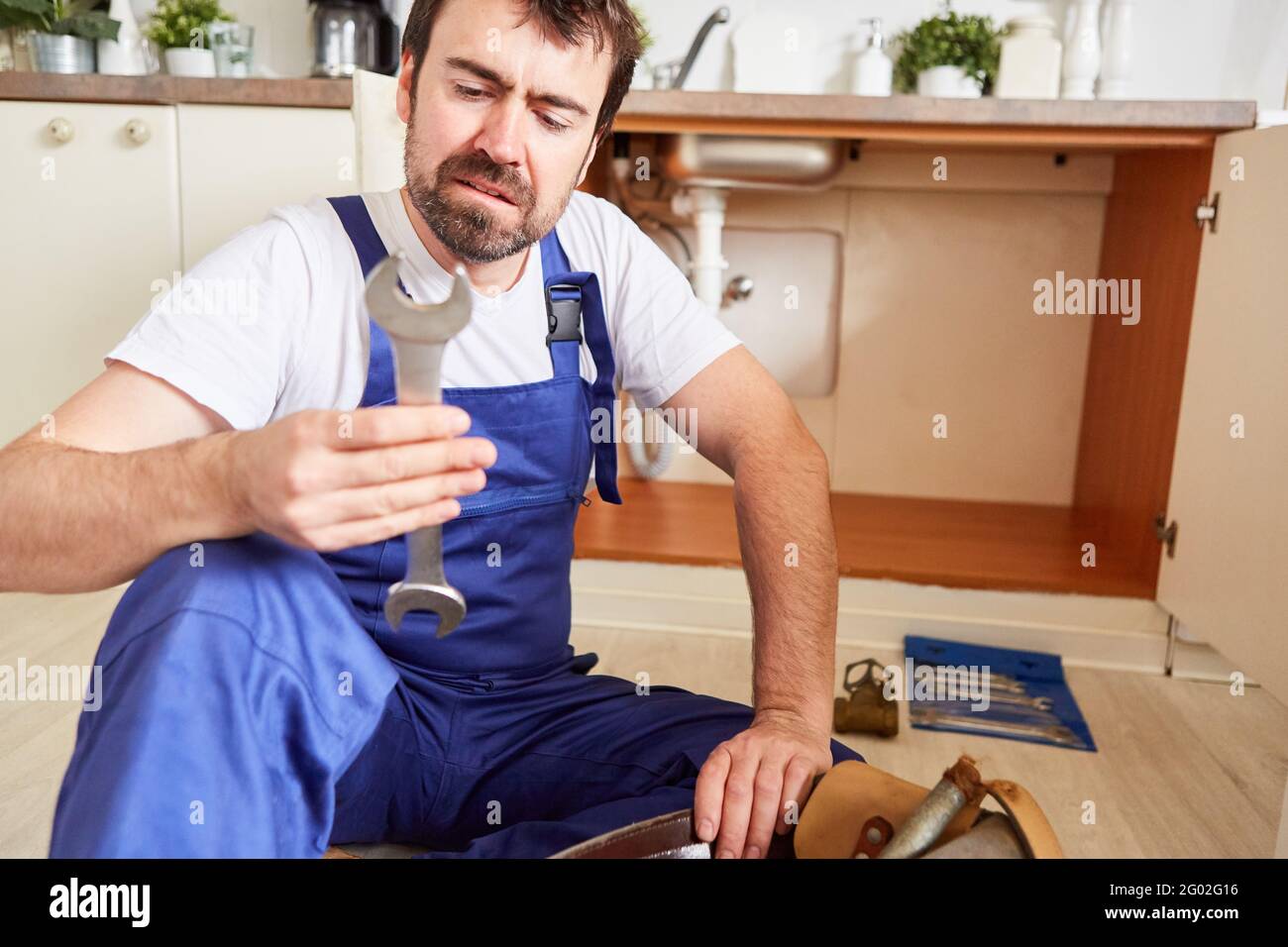 Handyman unsafe holds a wrench while repairing the broken sink Stock ...