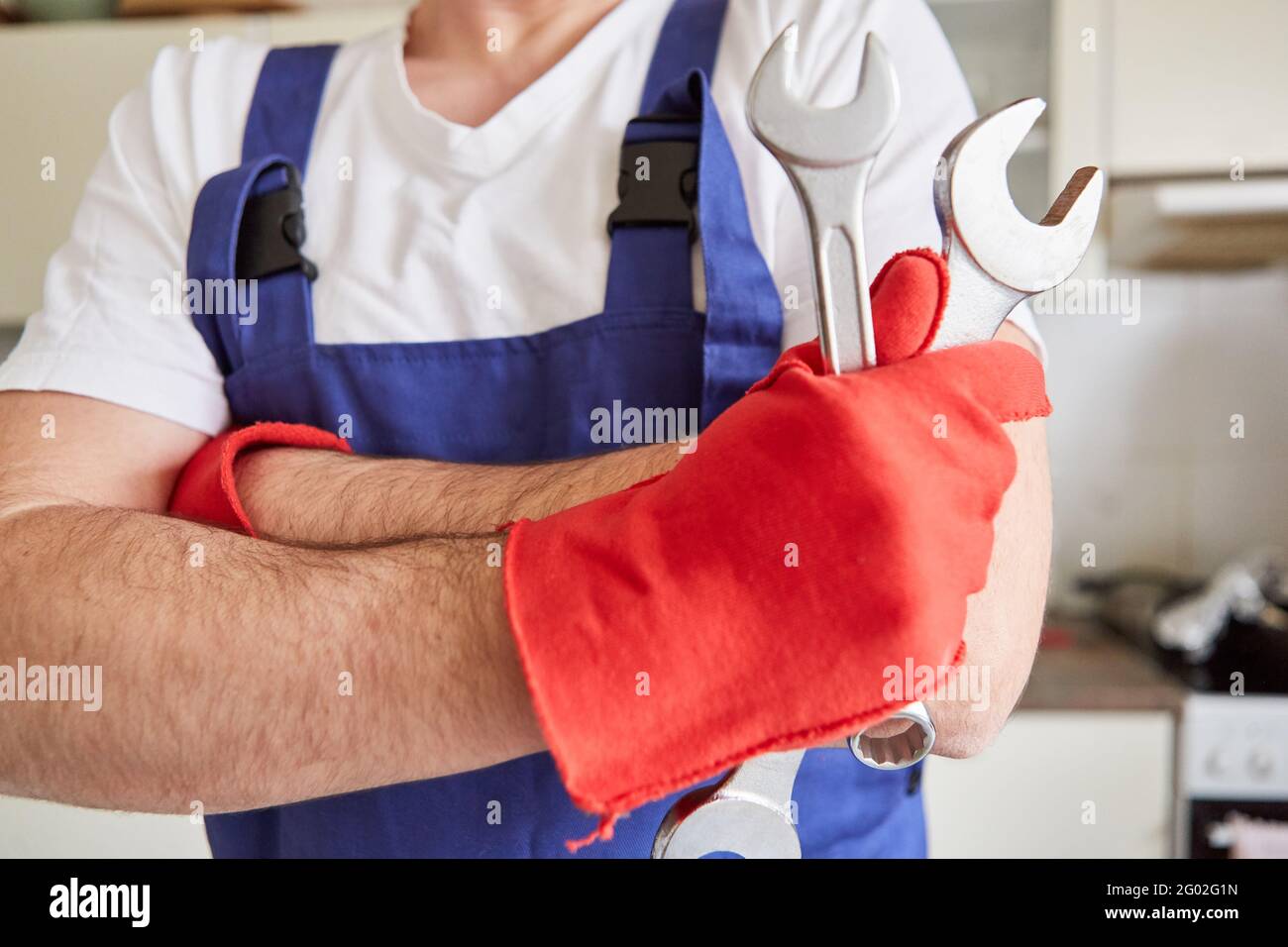 Handyman with two wrenches and red gloves Stock Photo - Alamy