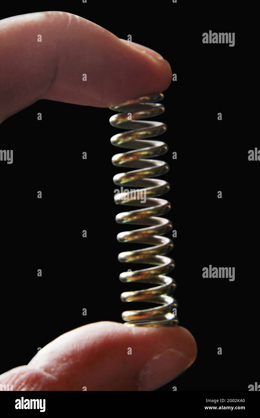 Hand squeezes a metal spring hi-res stock photography and images - Alamy