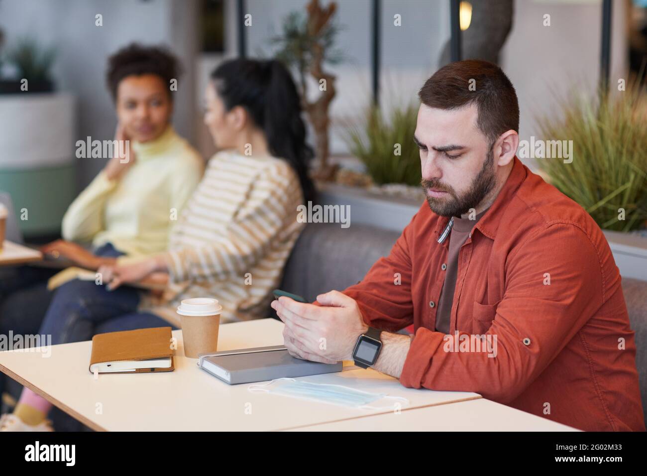 Portrait of bearded man working at table in cafe and looking at ...