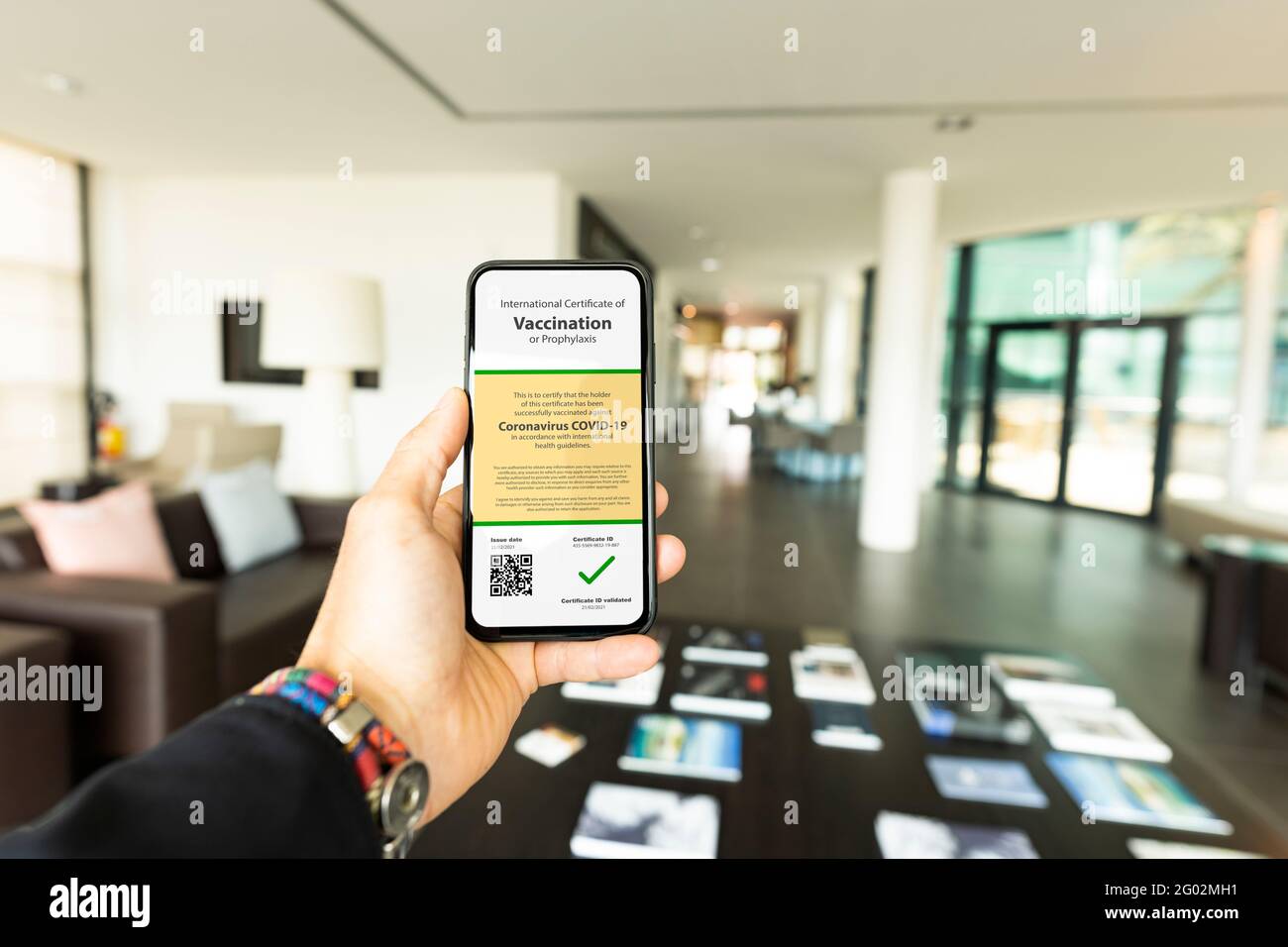 Human hand holding a smart phone with a Certificate of Vaccination ...