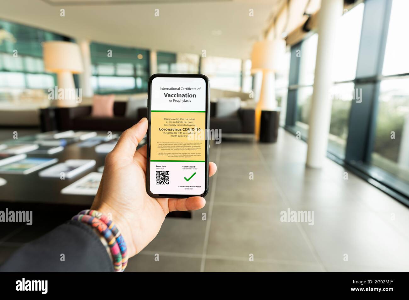 Human hand holding a smart phone with a Certificate of Vaccination ...