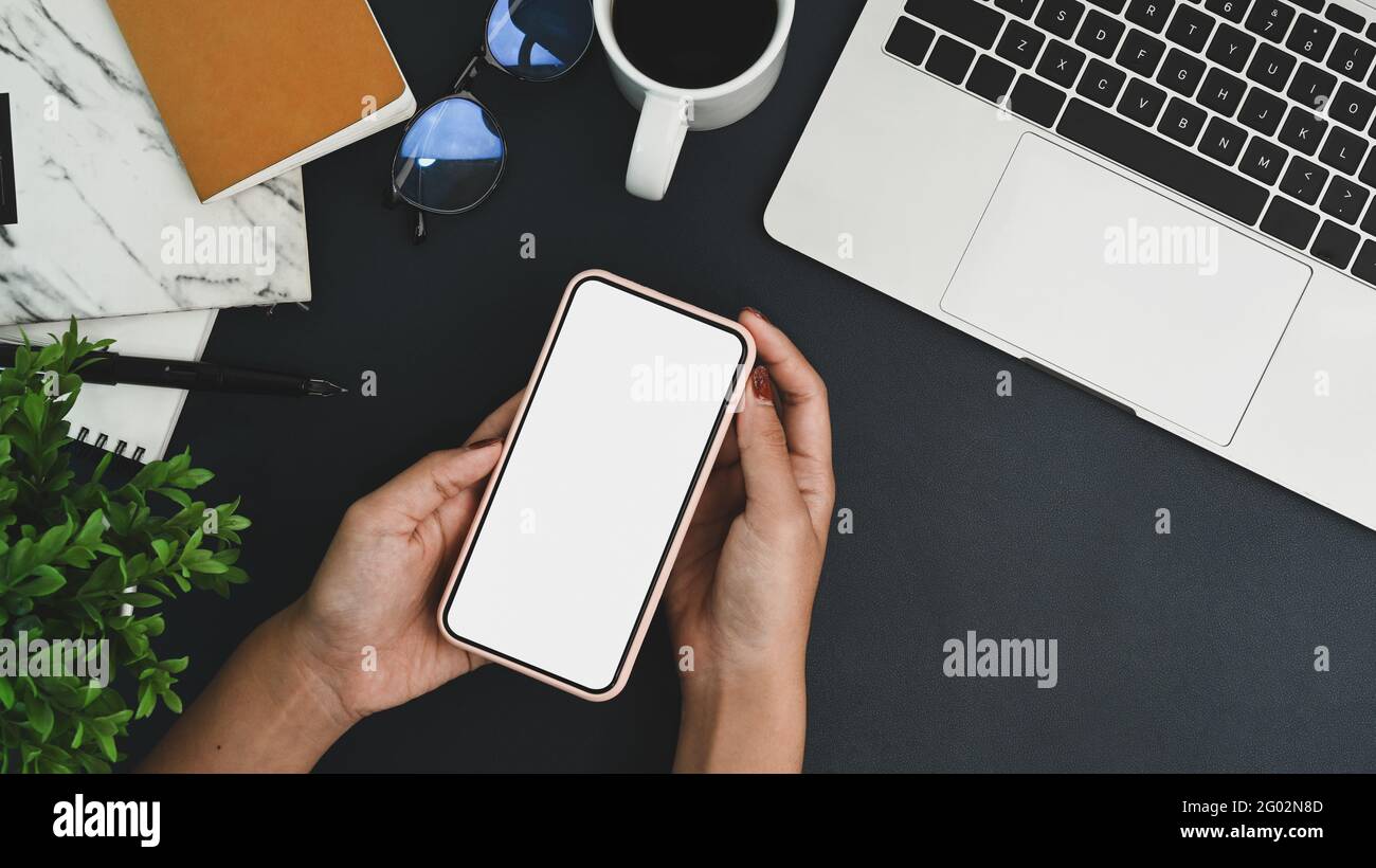 Above view female hands holding mock up smart phone with white screen ...