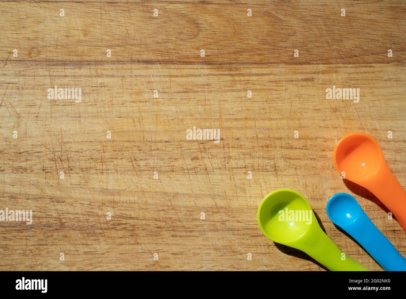 Used wooden kitchen cutting board with colorful measuring spoons in the ...