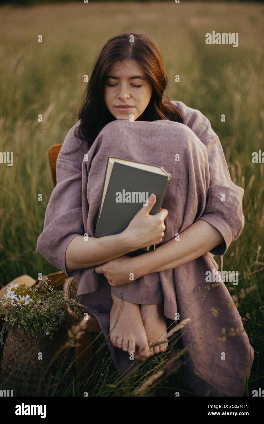 Beautiful woman in linen dress sitting on rustic chair and dreaming in ...