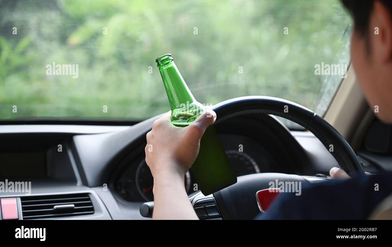 Man driving a car while holding a bottle of beer. Driving under the ...