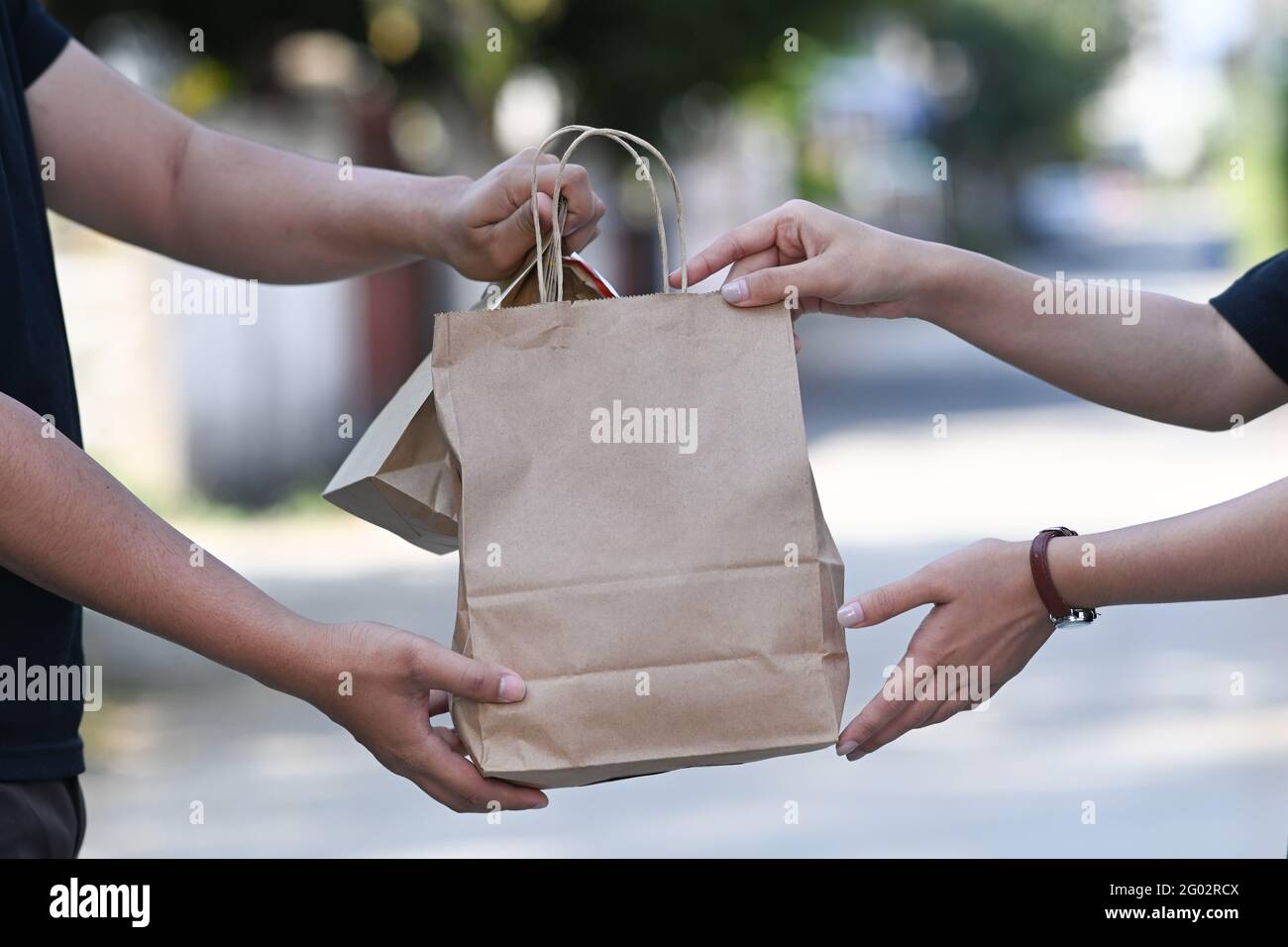 Close up view deliver man handing bag of food to a female customer ...