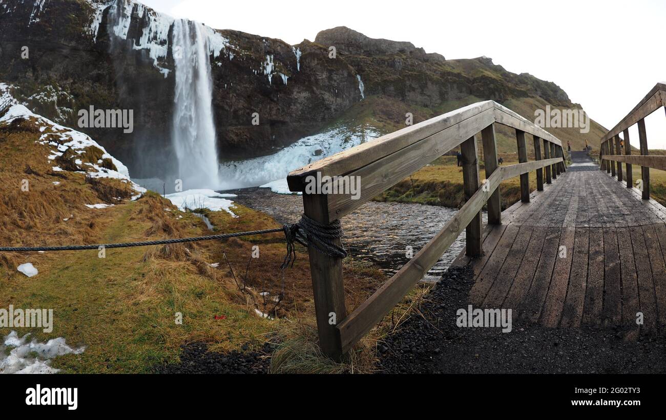 View of a wooden bridge over the river and scenic Seljalandsfoss ...
