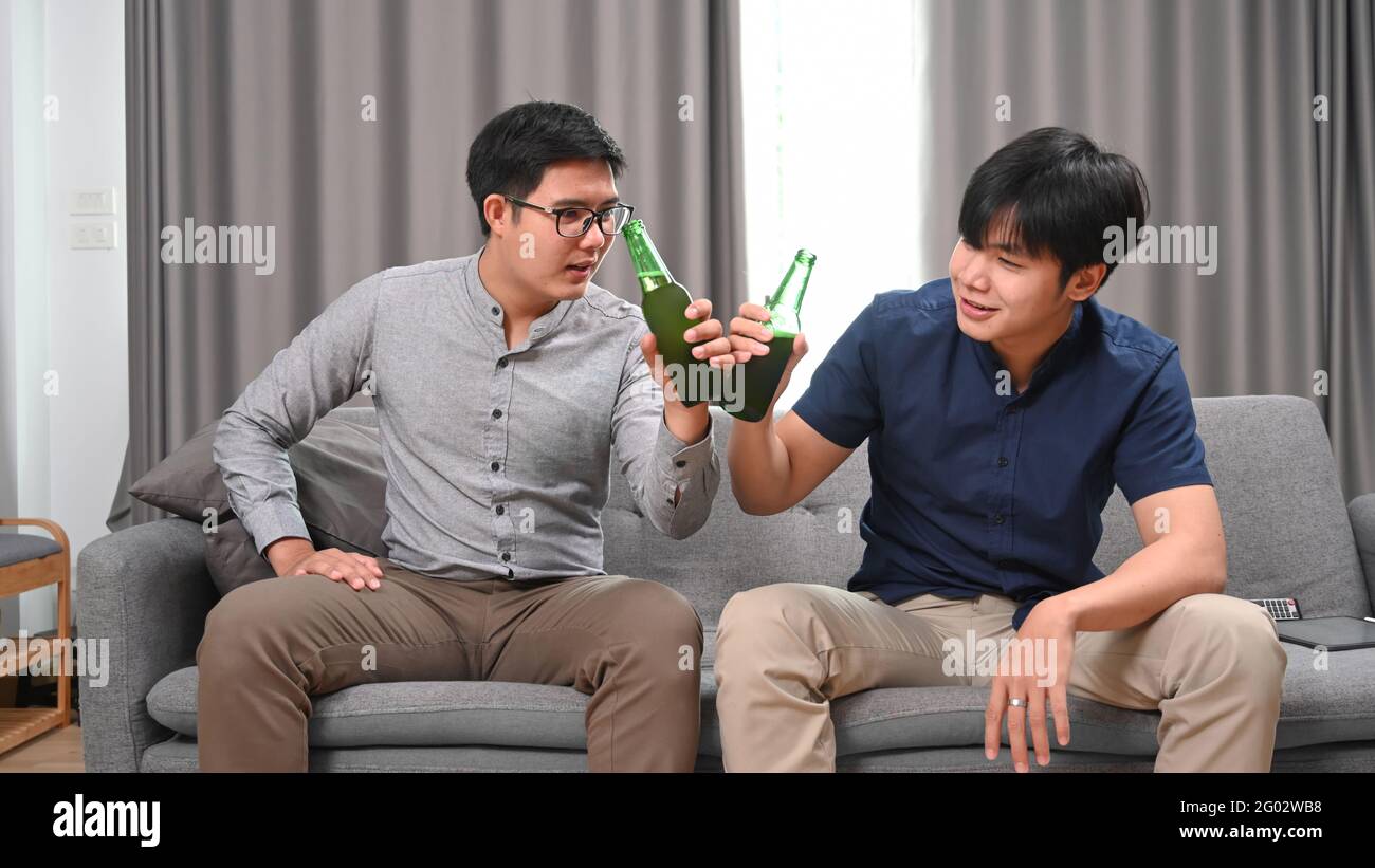 Happy two men drinking beer while sitting on sofa Stock Photo - Alamy