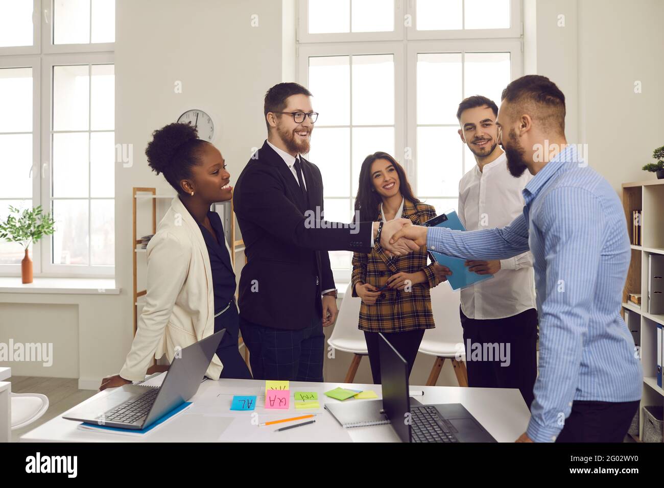 Male leader of a multiracial business team greets a new team member ...