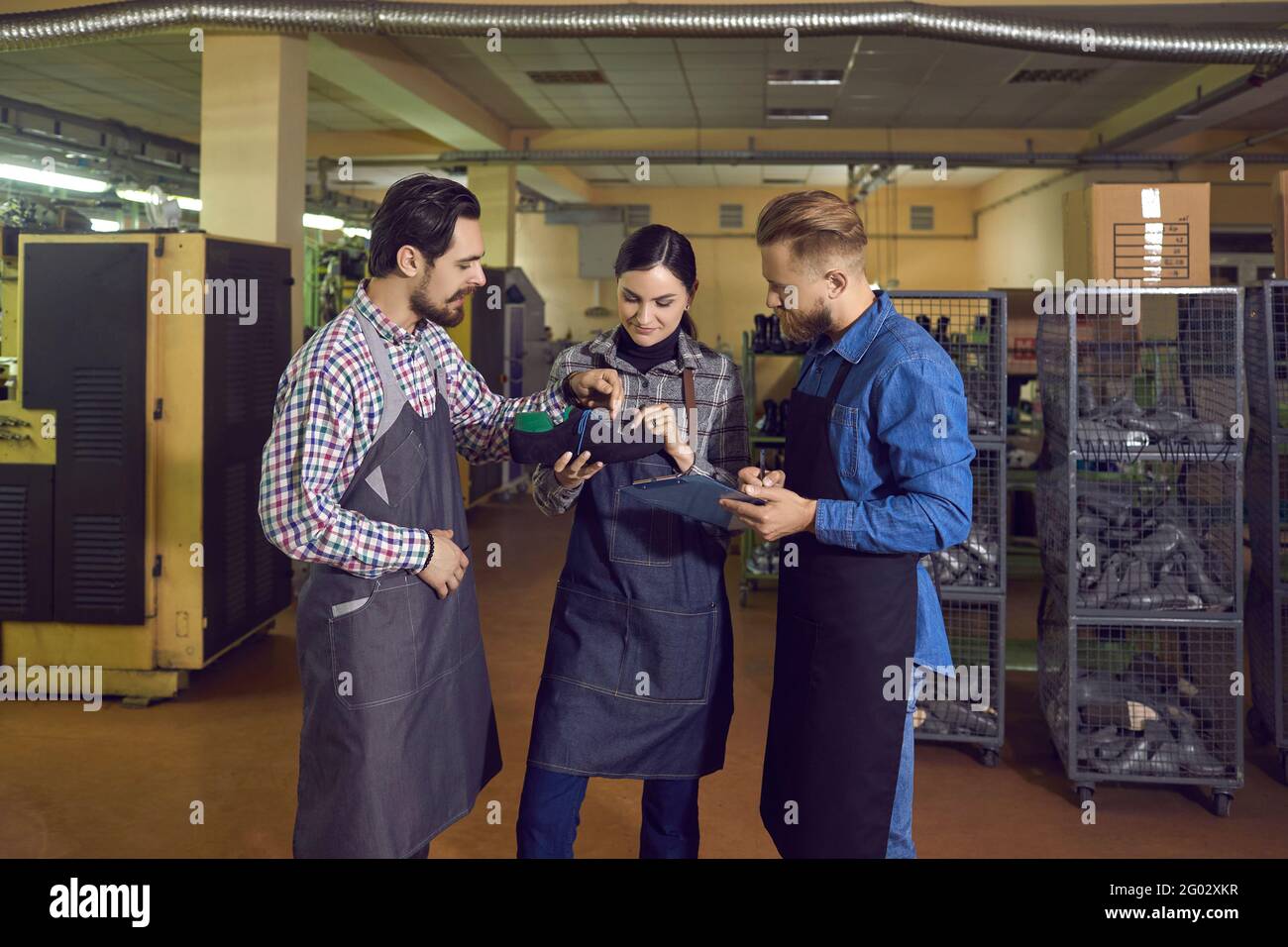 Shoemaker team working at shoe factory inspecting shoes talking and ...