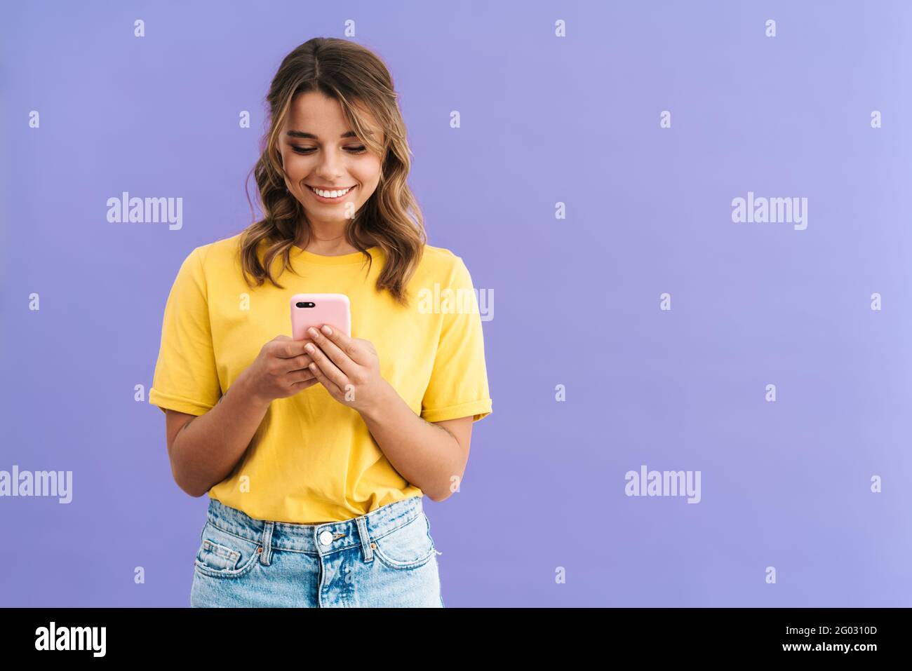 Happy beautiful girl smiling while using mobile phone isolated over ...