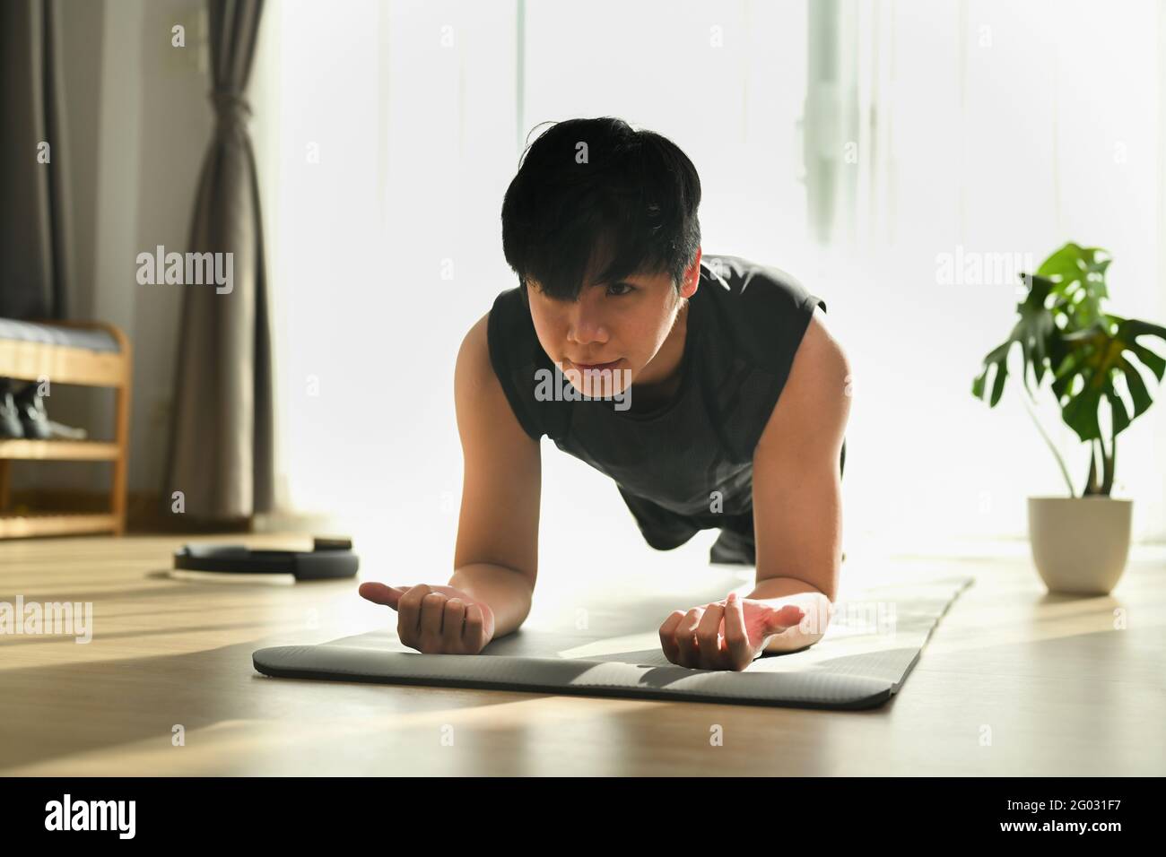 Fitness man doing plank exercise on mat during morning training at home ...