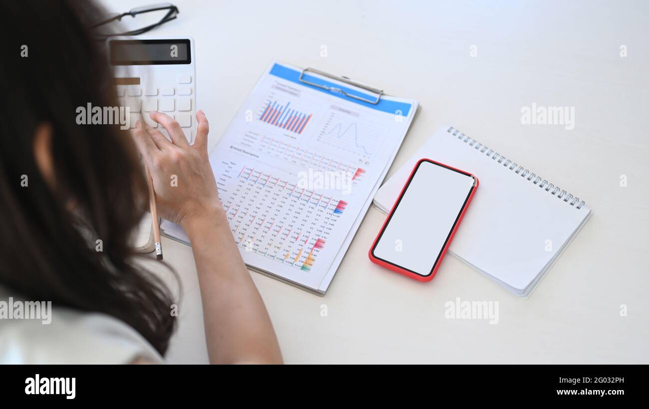 Rear view of female accountant using calculator and analyzing finance ...