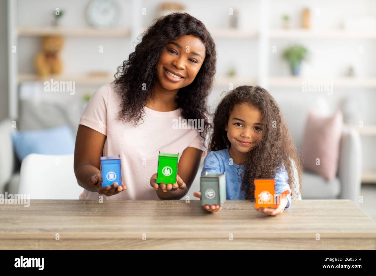 Portrait of black mother and her cute daughter showing eco-friendly ...