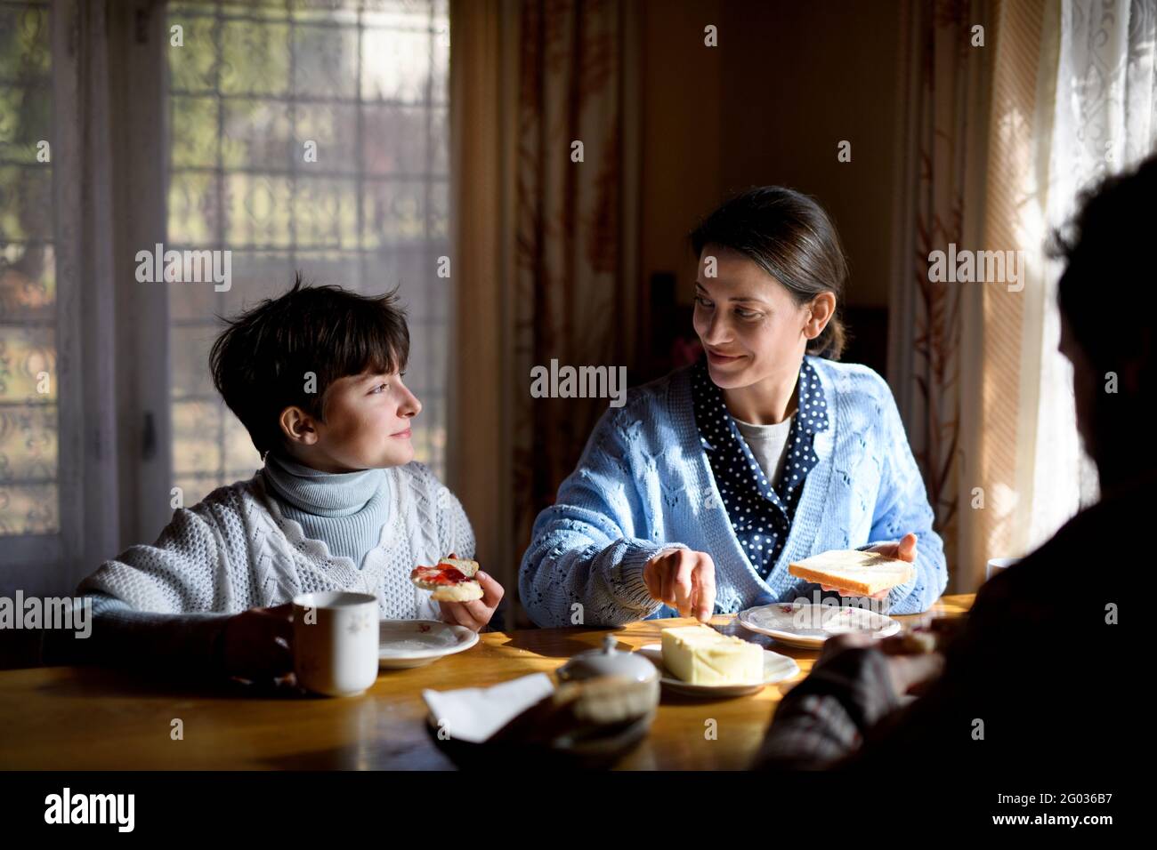 Portrait of happy poor small girl with parents eating indoors at home ...