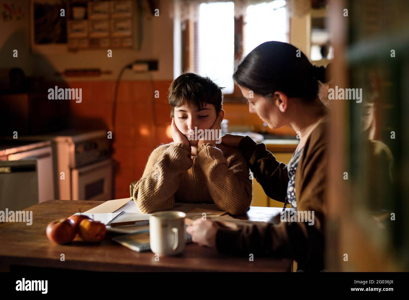 Poor mature mother and small daughter learning indoors at home, poverty ...