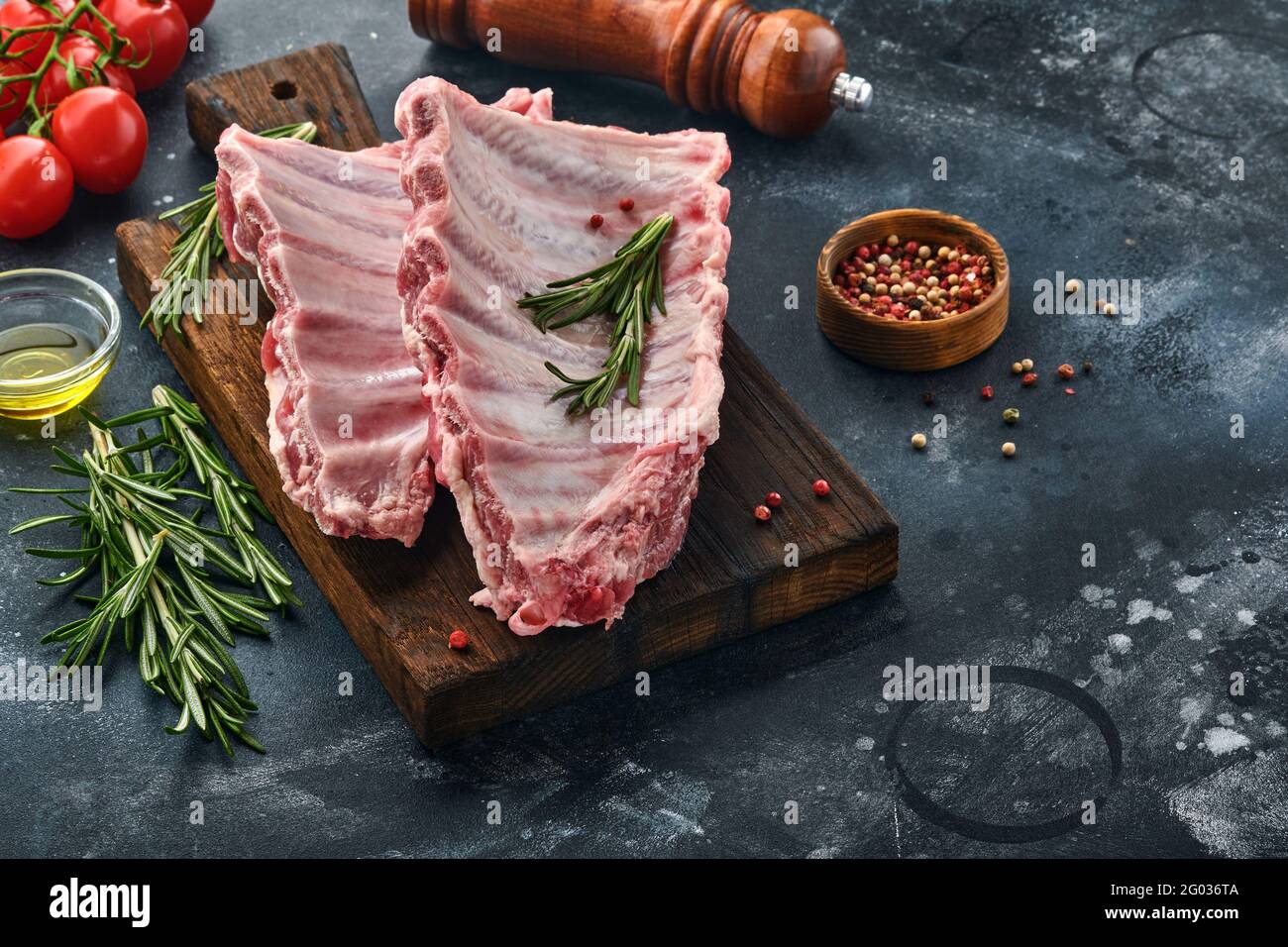 Raw pork ribs or fresh uncooked meat with spices on black wooden tray ...