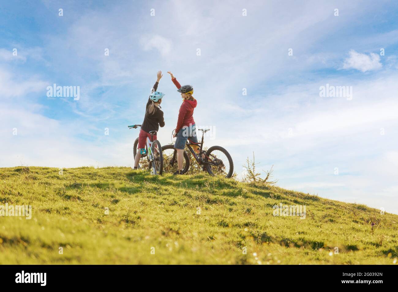 Two happy woman high five over the sunset after a successful mountain ...