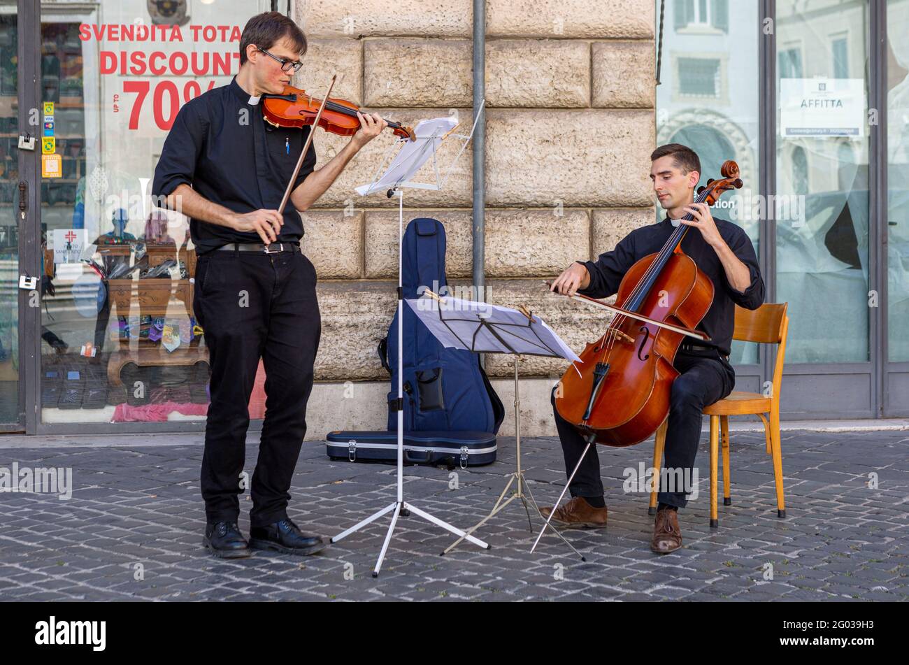 Two young Catholic priests play violin and cello in the street Stock ...