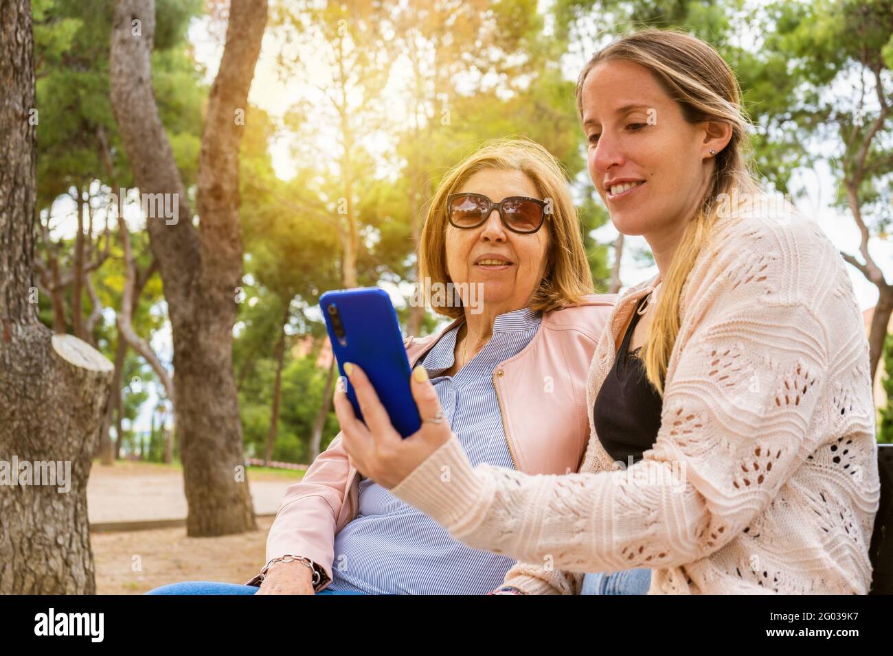 Happy mother and her daughter looking smartphone making a video call or ...