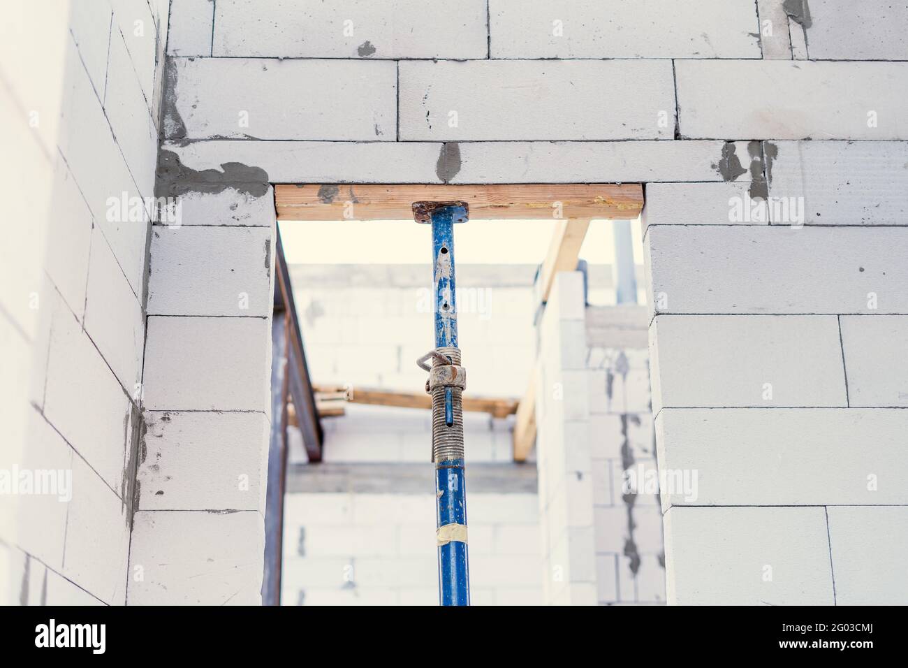 A construction jack supports a white cinder block wall in an unfinished ...