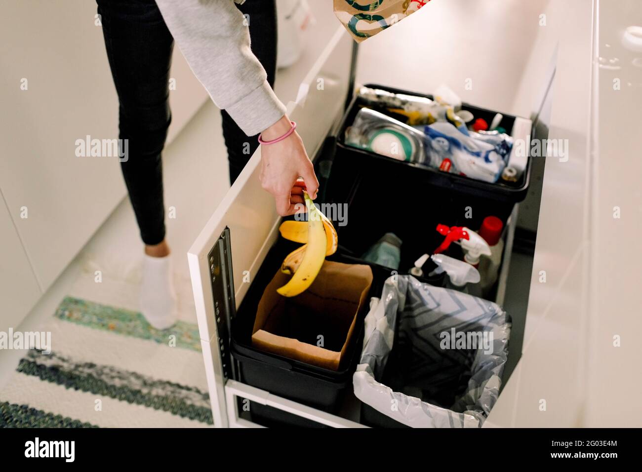 Girl throwing banana peel in garbage can at home Stock Photo - Alamy