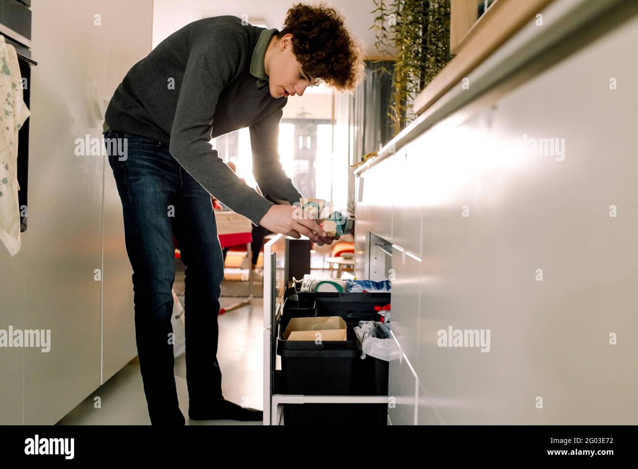 Full length of teenage boy throwing garbage in bin at home Stock Photo ...