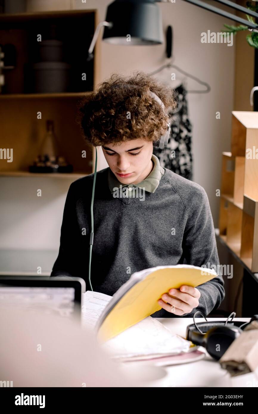 Boy wearing headphones while studying at home Stock Photo - Alamy