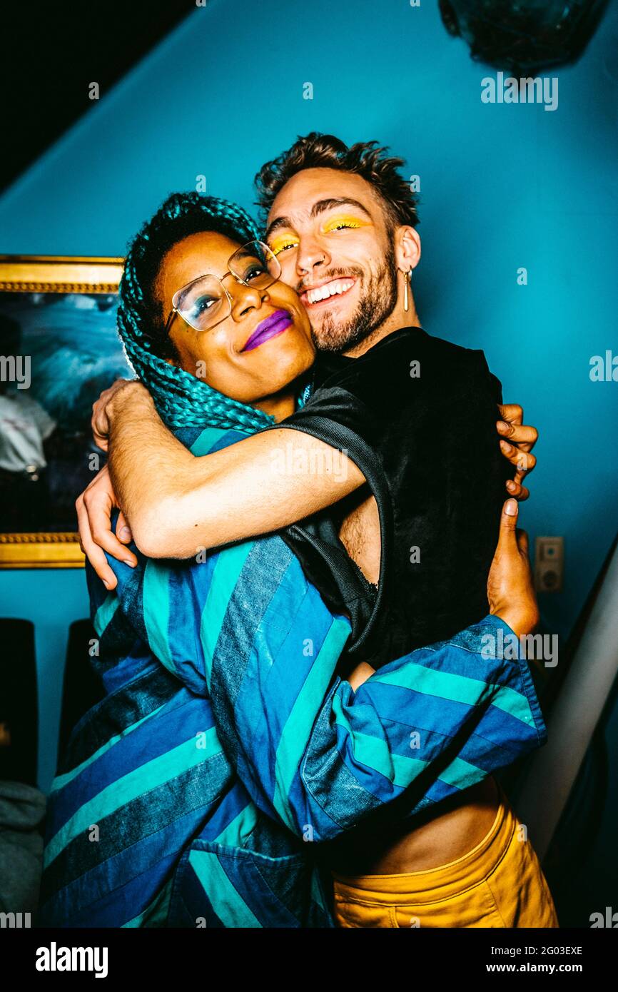 Portrait of happy male and female friends hugging with cheek to cheek ...