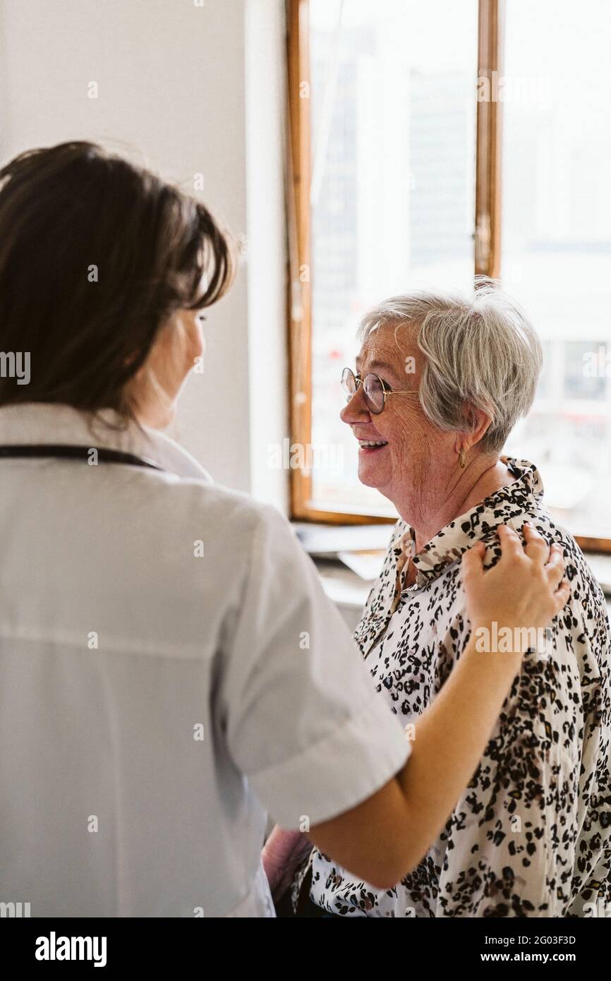 Female healthcare worker comforting senior patient at medical clinic ...