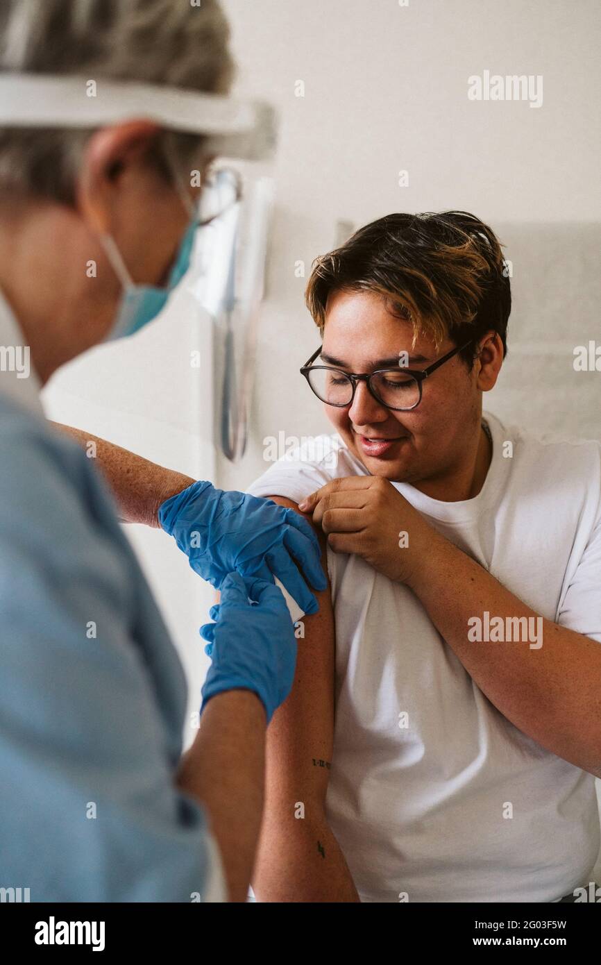 Senior female medical expert injecting male patient during COVID-19 ...
