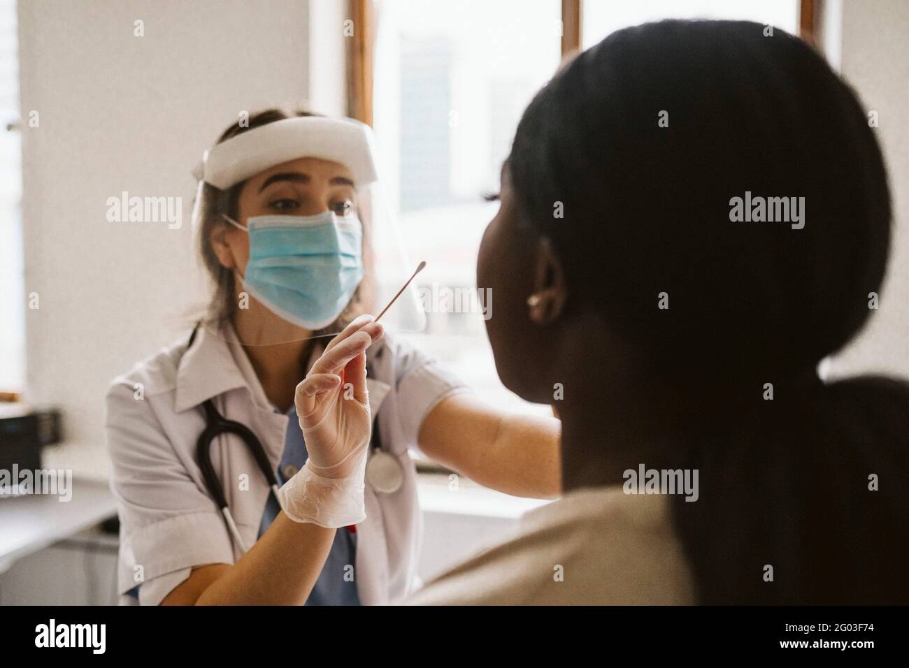 Female doctor wearing protective mask and face shield doing patient's ...