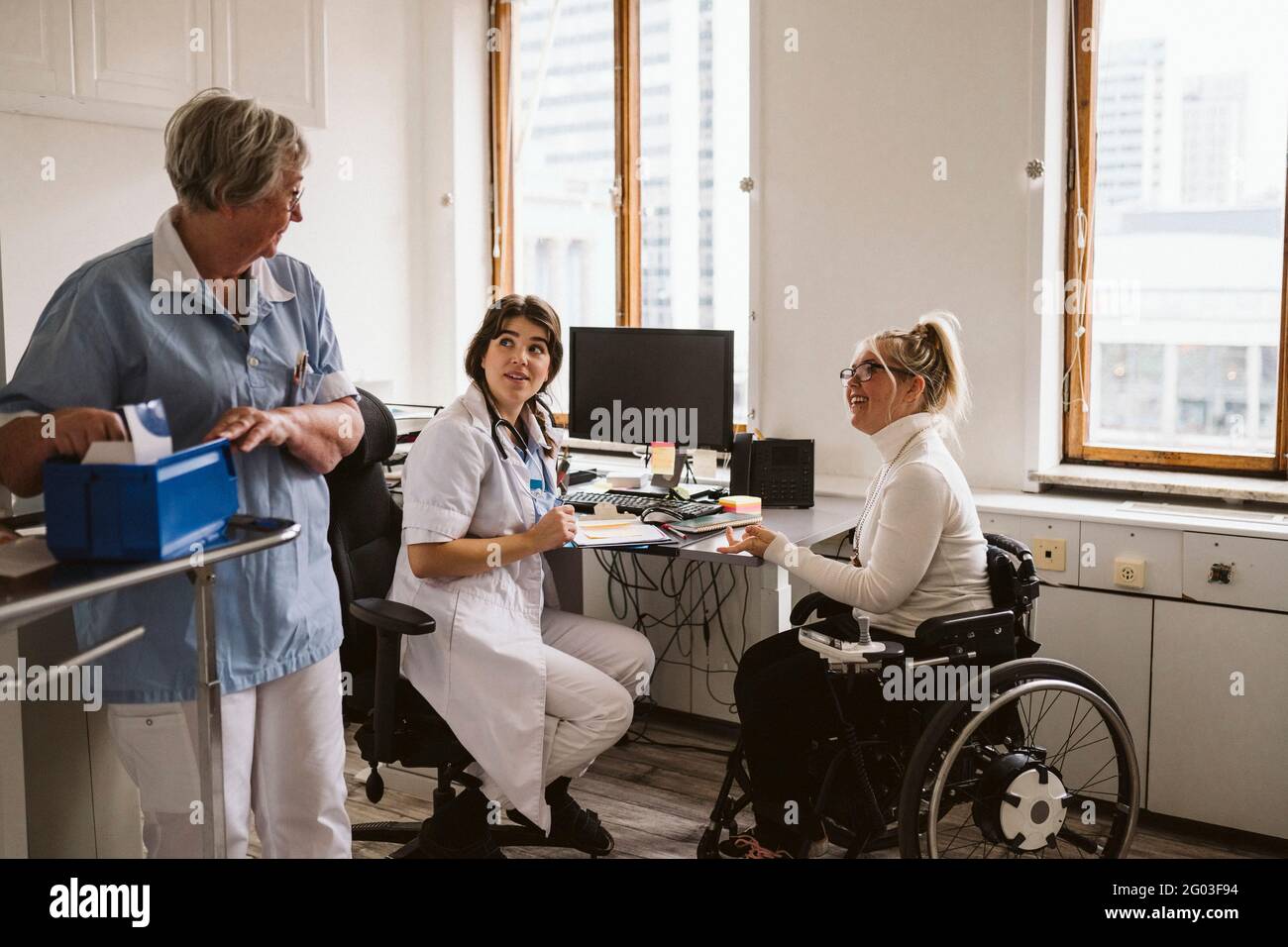 Female healthcare worker sitting with disabled patient talking with ...
