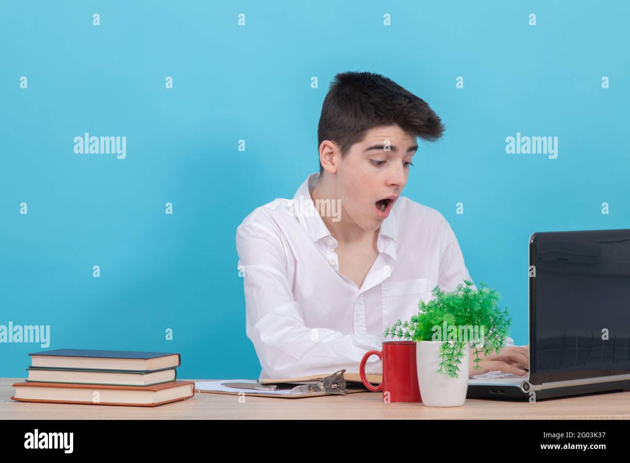 young student at the desk with computer and books and expression of ...