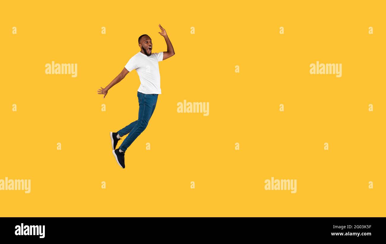 Black Guy Jumping Looking Aside In Shock On Yellow Background Stock ...