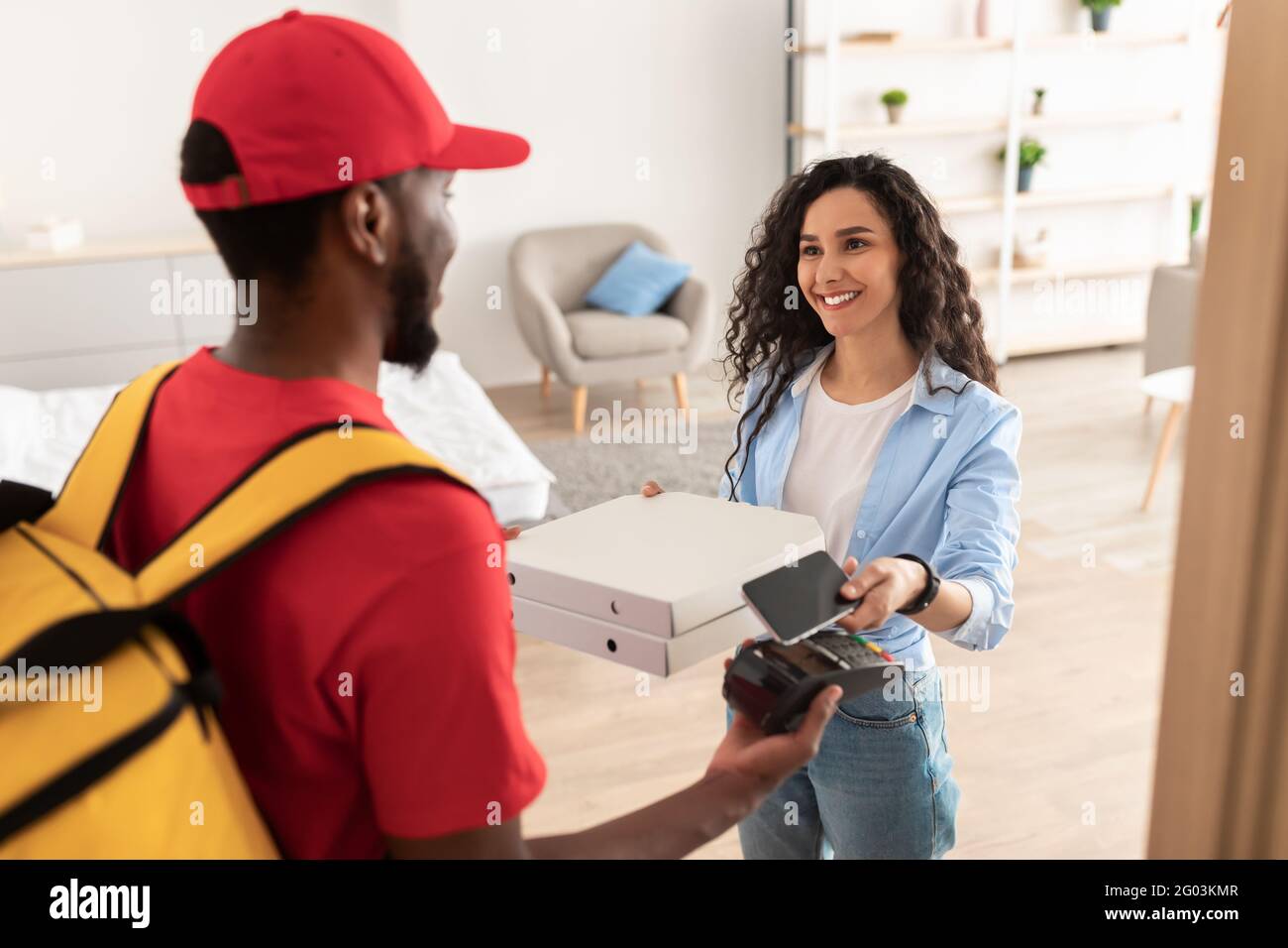 Black delivery man holding POS machine for payment Stock Photo - Alamy