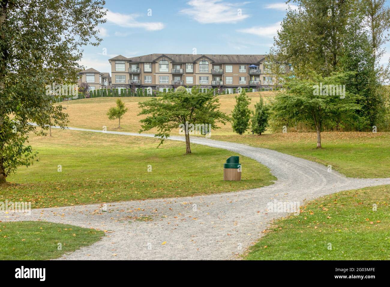 Gravel pathway in a park in front of residential building on the hill ...